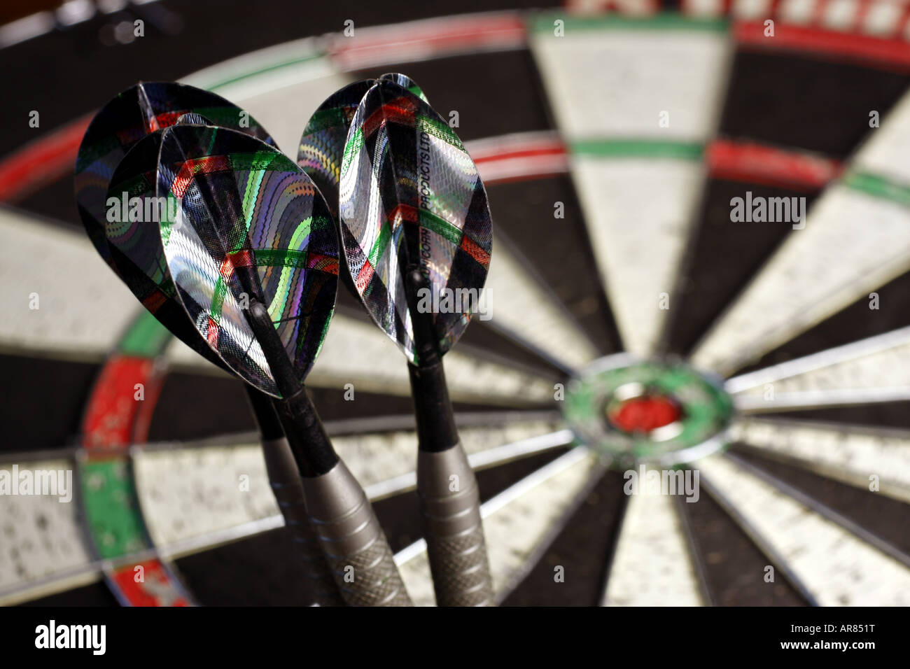 Three darts with a dartboard behind Stock Photo - Alamy