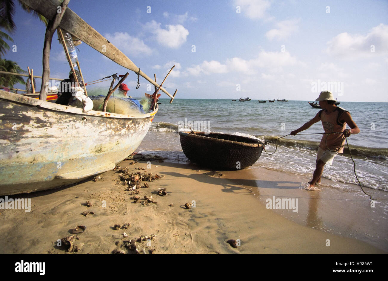 Man Pulling Fishing Boat Onto Beach Stock Photo - Alamy