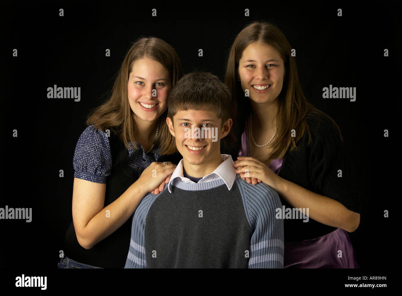 Two sisters and their brother smiling Stock Photo - Alamy