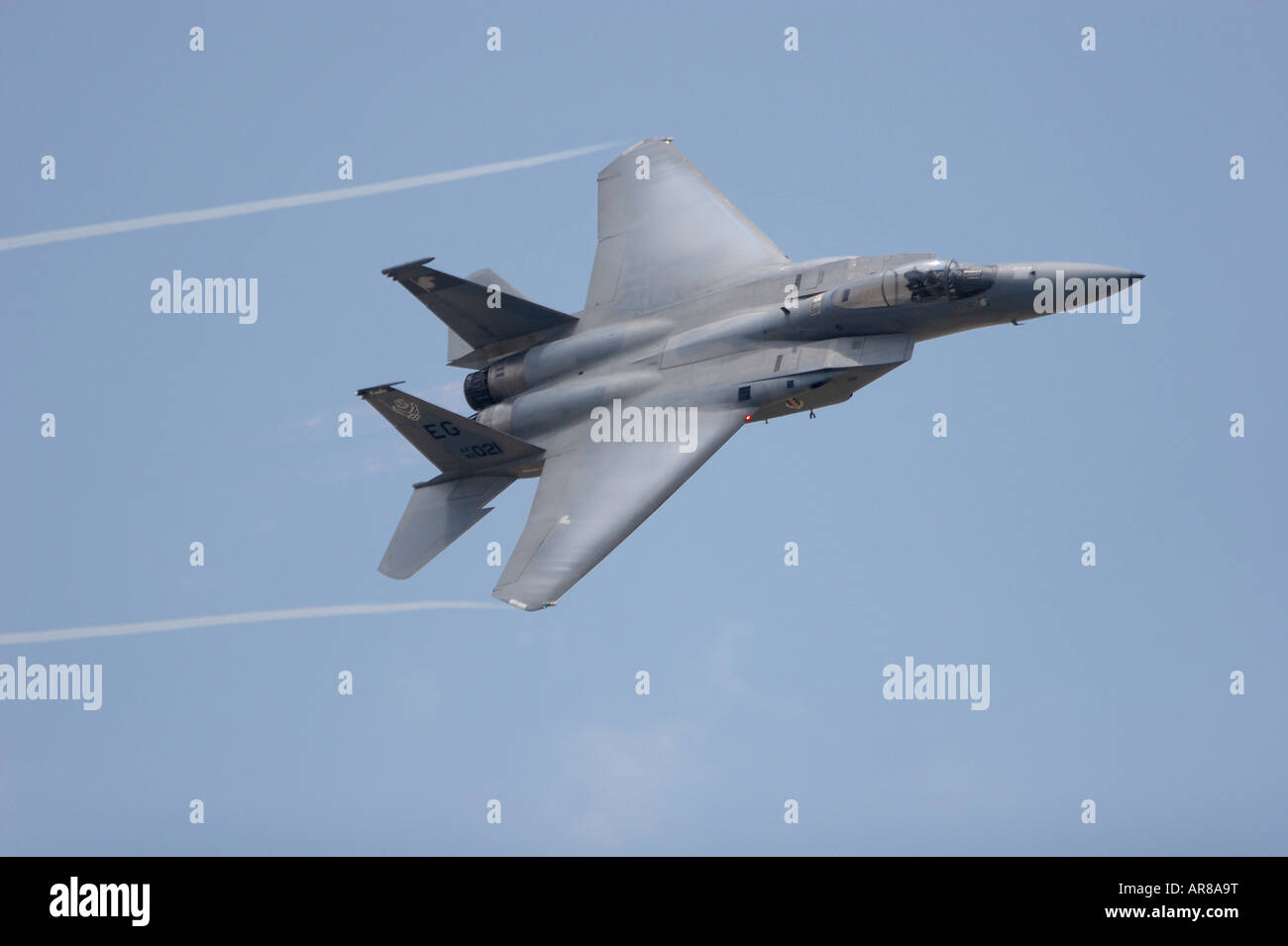 An F-15 Strike Eagle flying with vapor trailing from its wing tips ...