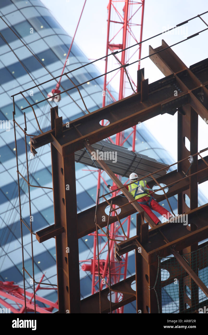 Construction worker maneuvers load from crane high up on new ...
