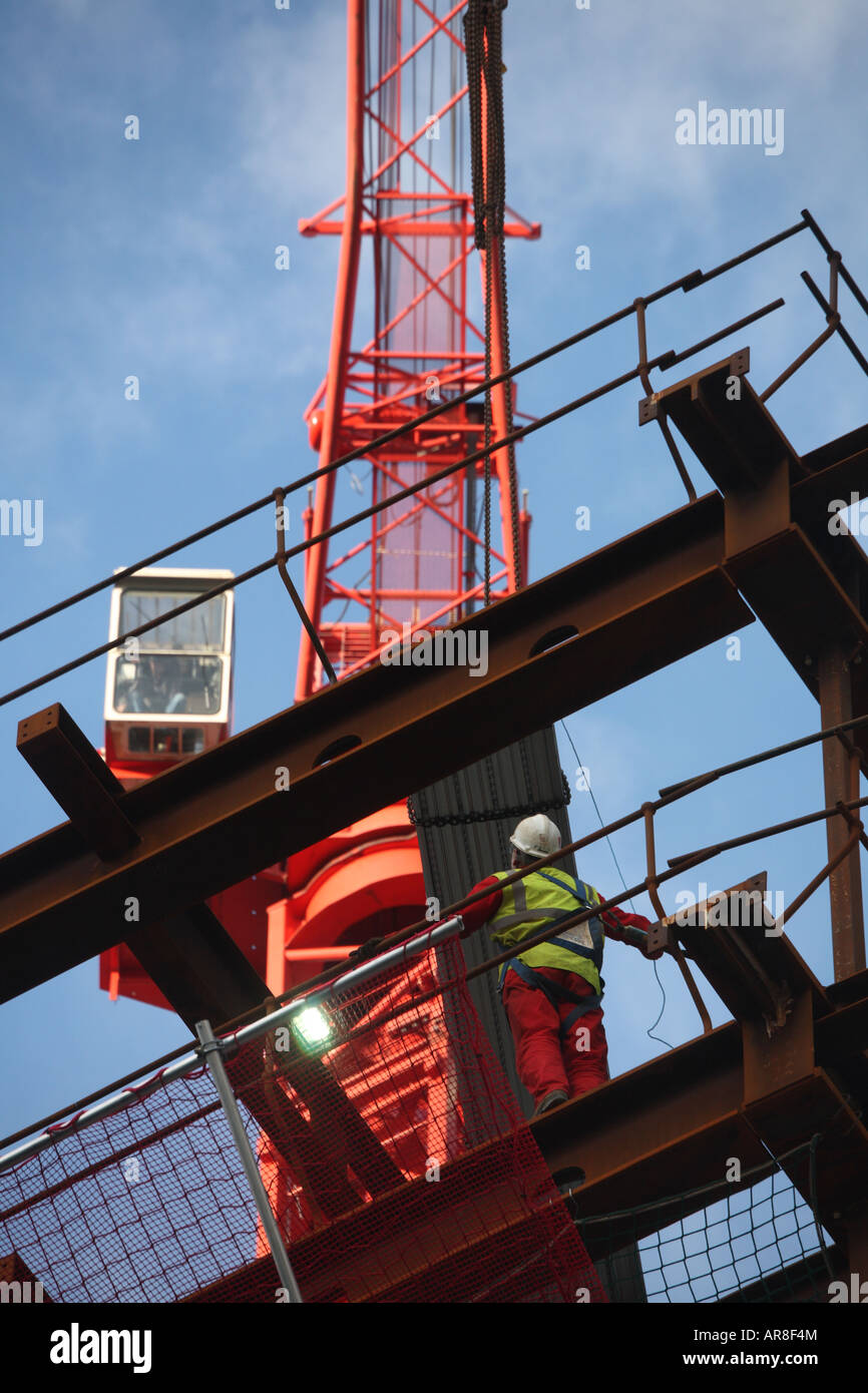 Construction worker maneuvers load from crane high up on new ...