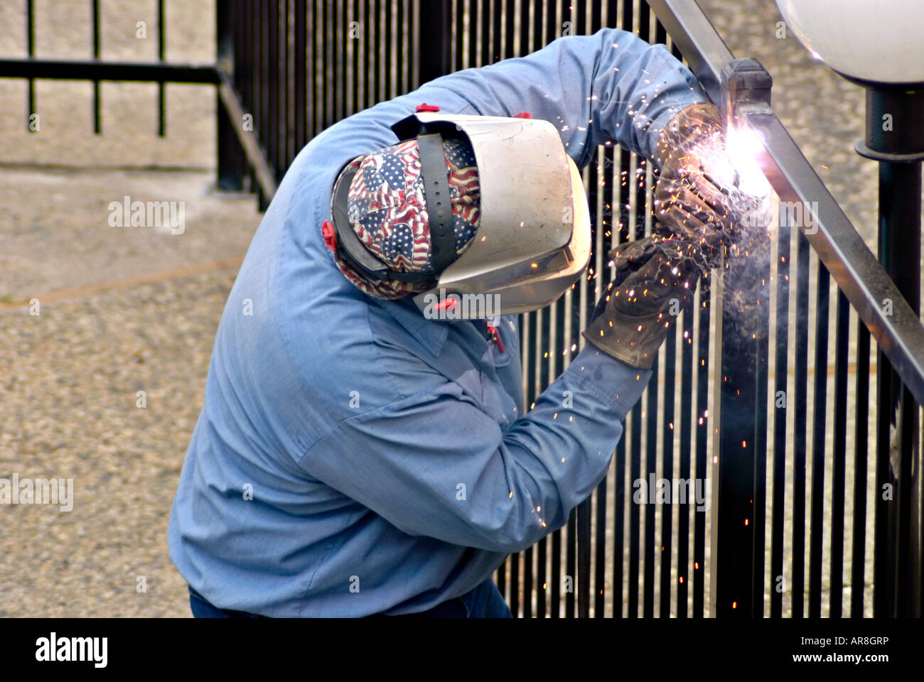Fence installation worker welds a seal on a new fence post Stock Photo ...