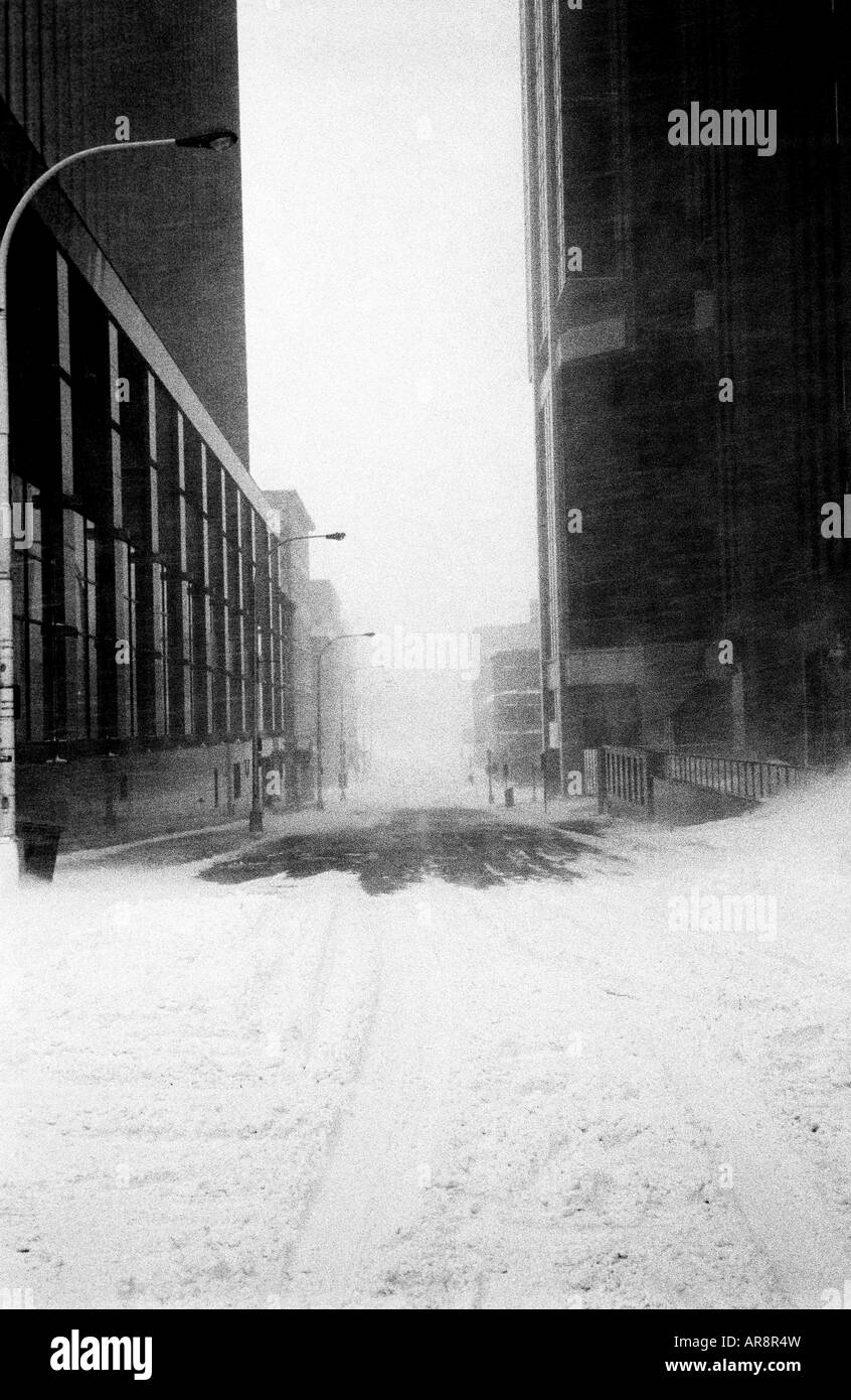 Empty downtown street with highrise buildings. Snow with tire tracks in ...