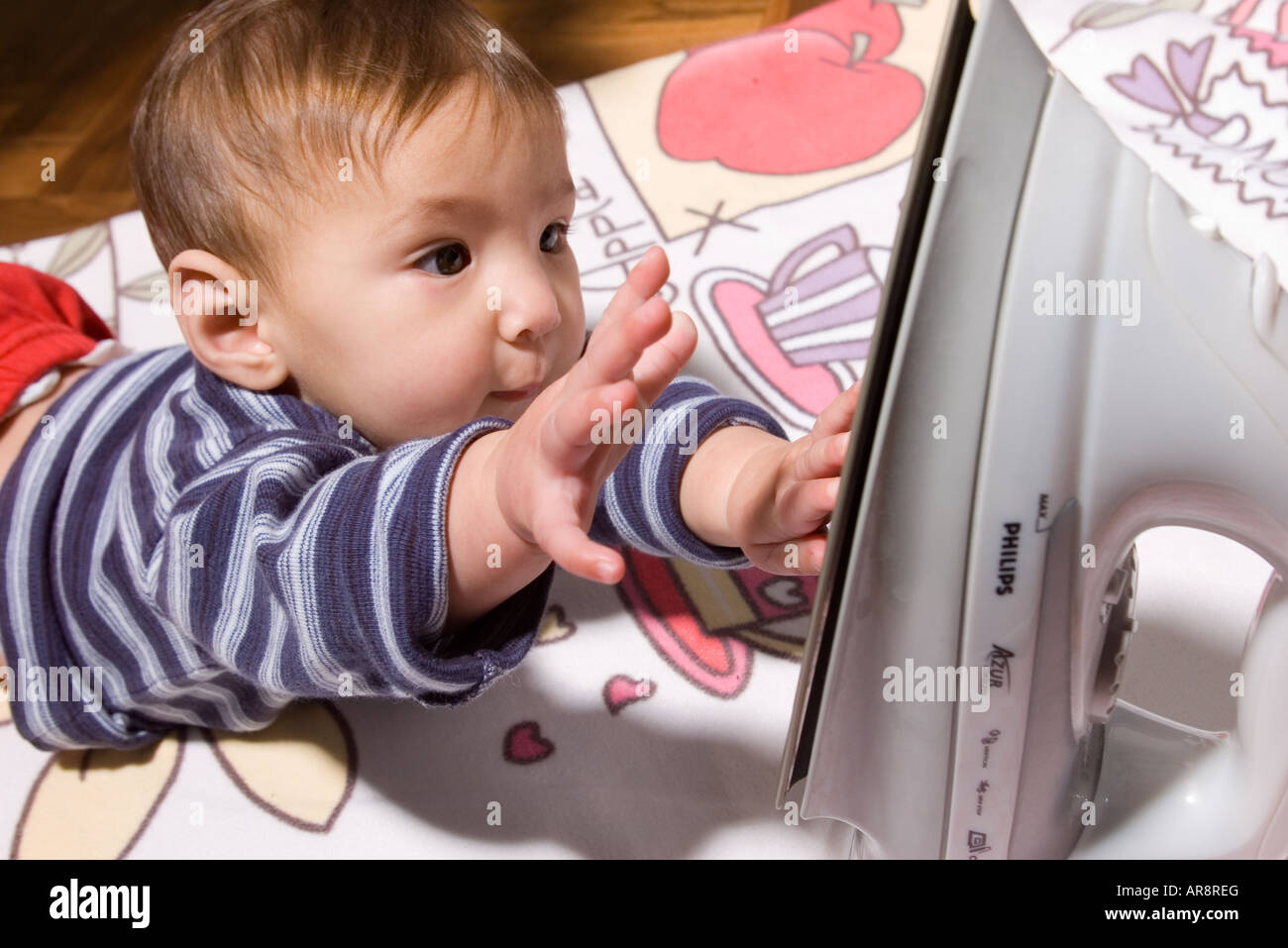 a baby is touching a hot iron Stock Photo - Alamy