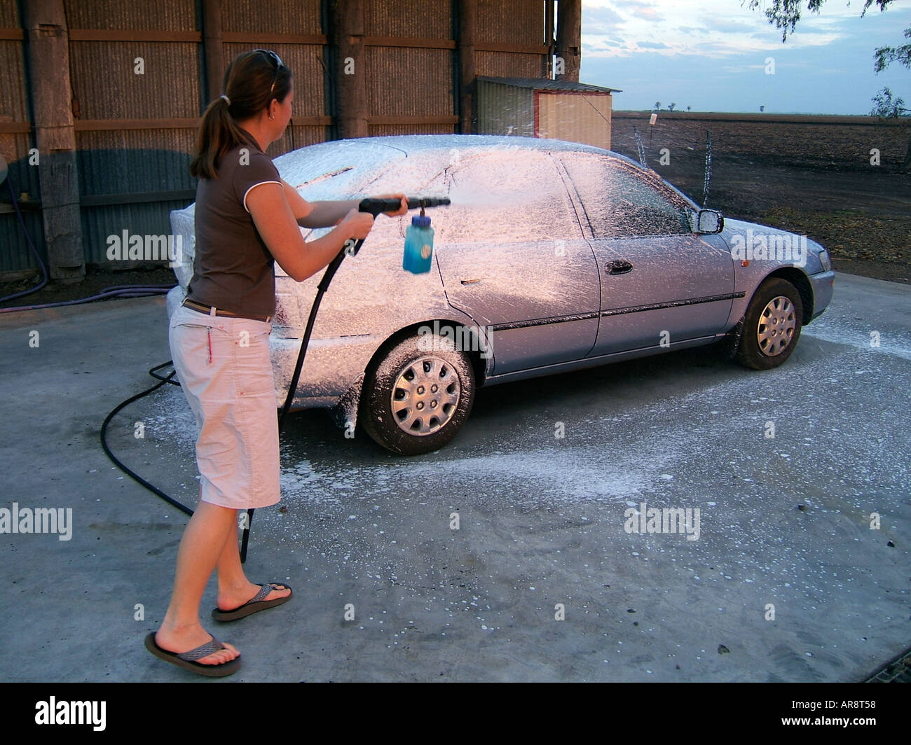 Young woman washing a car using a power hose Stock Photo - Alamy