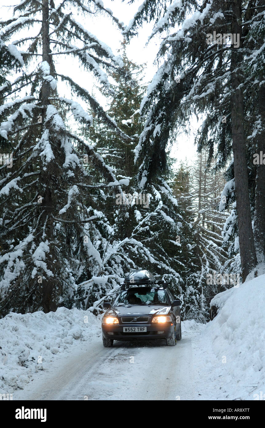 Car with ski box on driving using snowchains driving down a single ...