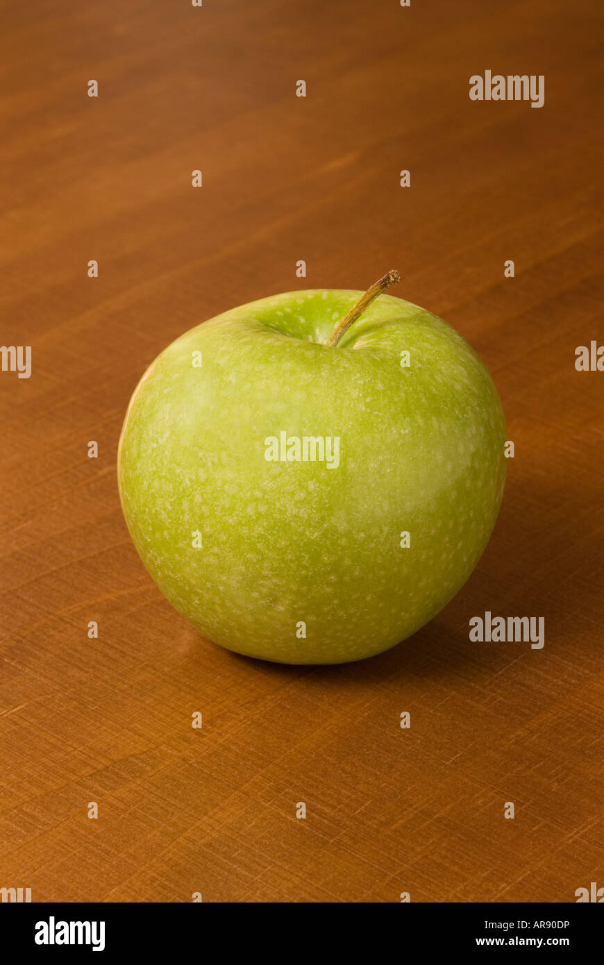 a single green apple on a wooden table Stock Photo - Alamy