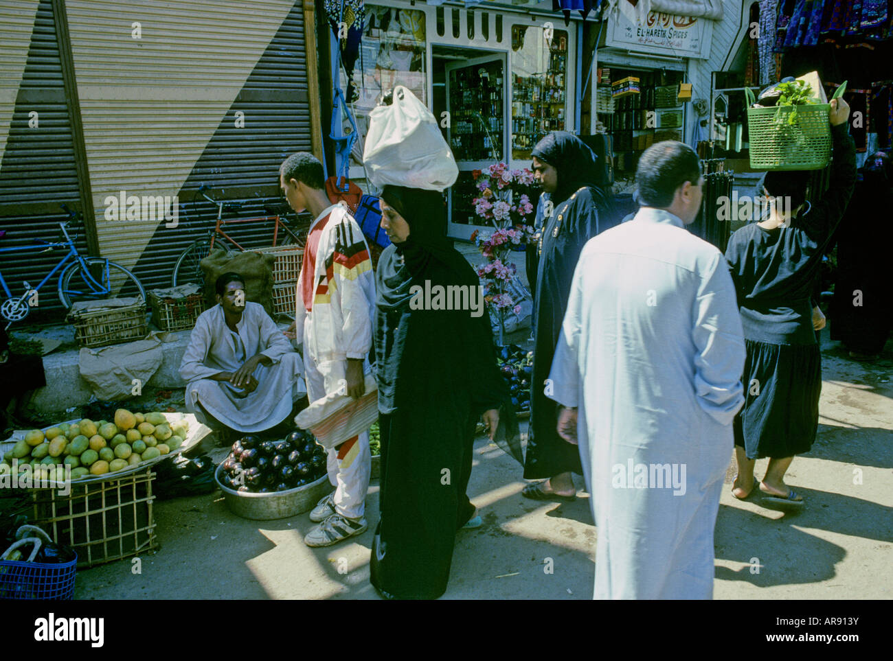 A fruit and vegetable trader sits in the shade in a street in Aswan ...