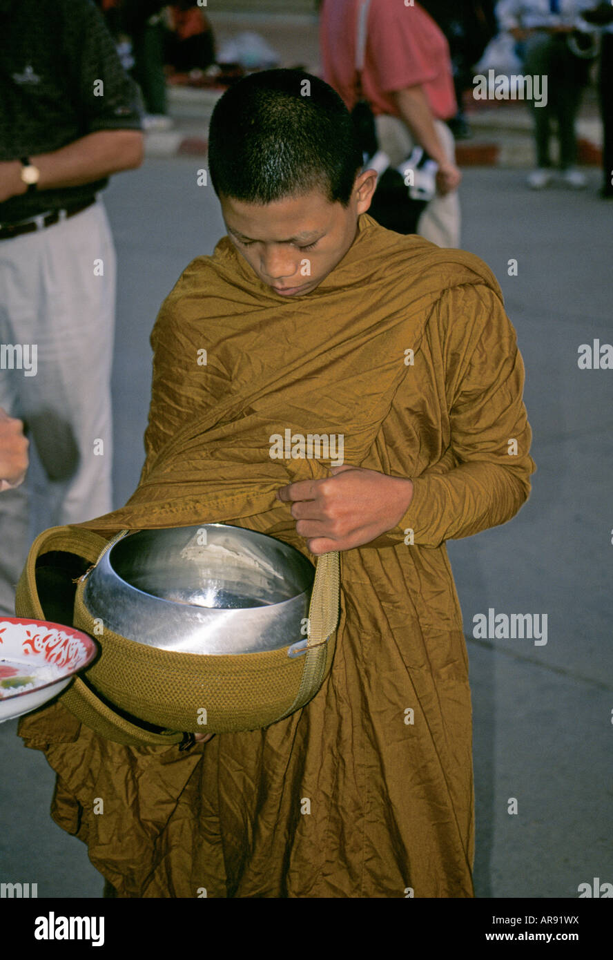 A young Buddhist monk begs on the streets for his daily alms and food ...