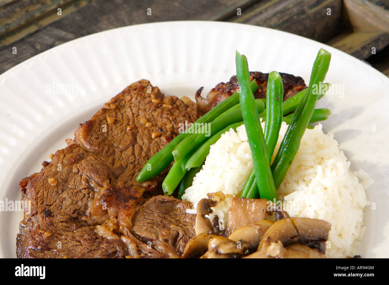Cooked Ribeye meal with rice, green beans and mushrooms on a white ...