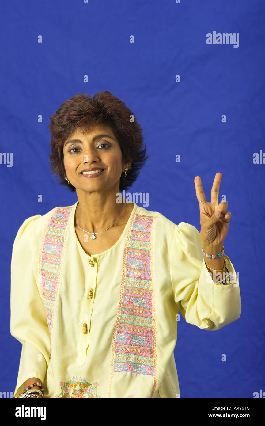 An Indian woman in ethnic clothing giving a peace sign gesture while ...