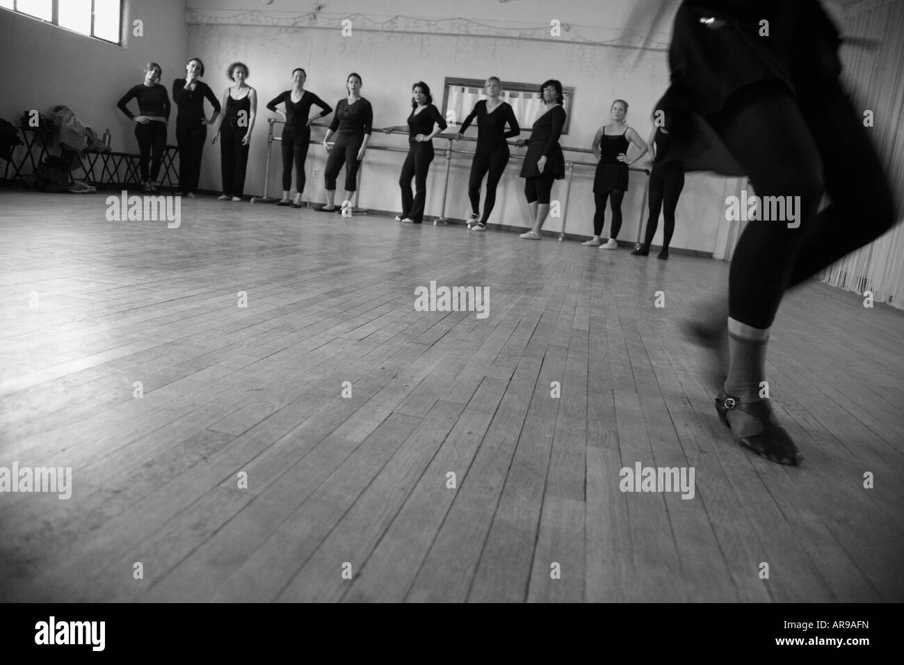 Women in ballet class watch dance instructor while waiting for their ...
