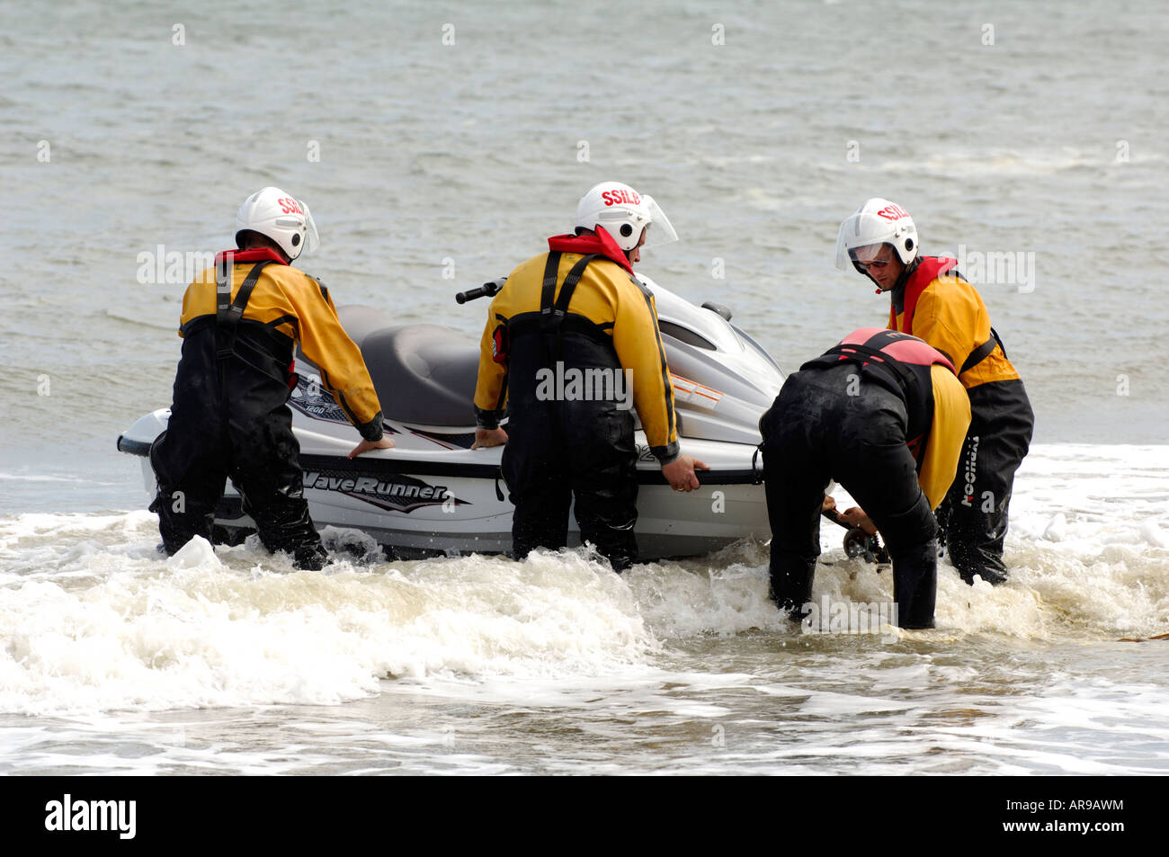 a lifeboat rnli crew members launching a small inshore rescue boat jet ...