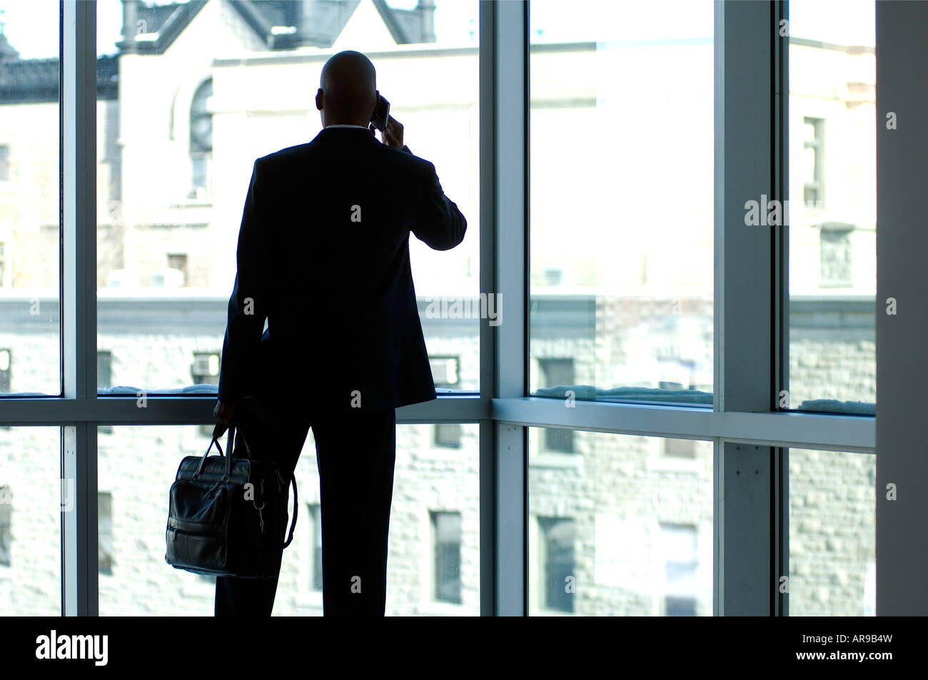 Businessman silhouetted in large office window Stock Photo - Alamy