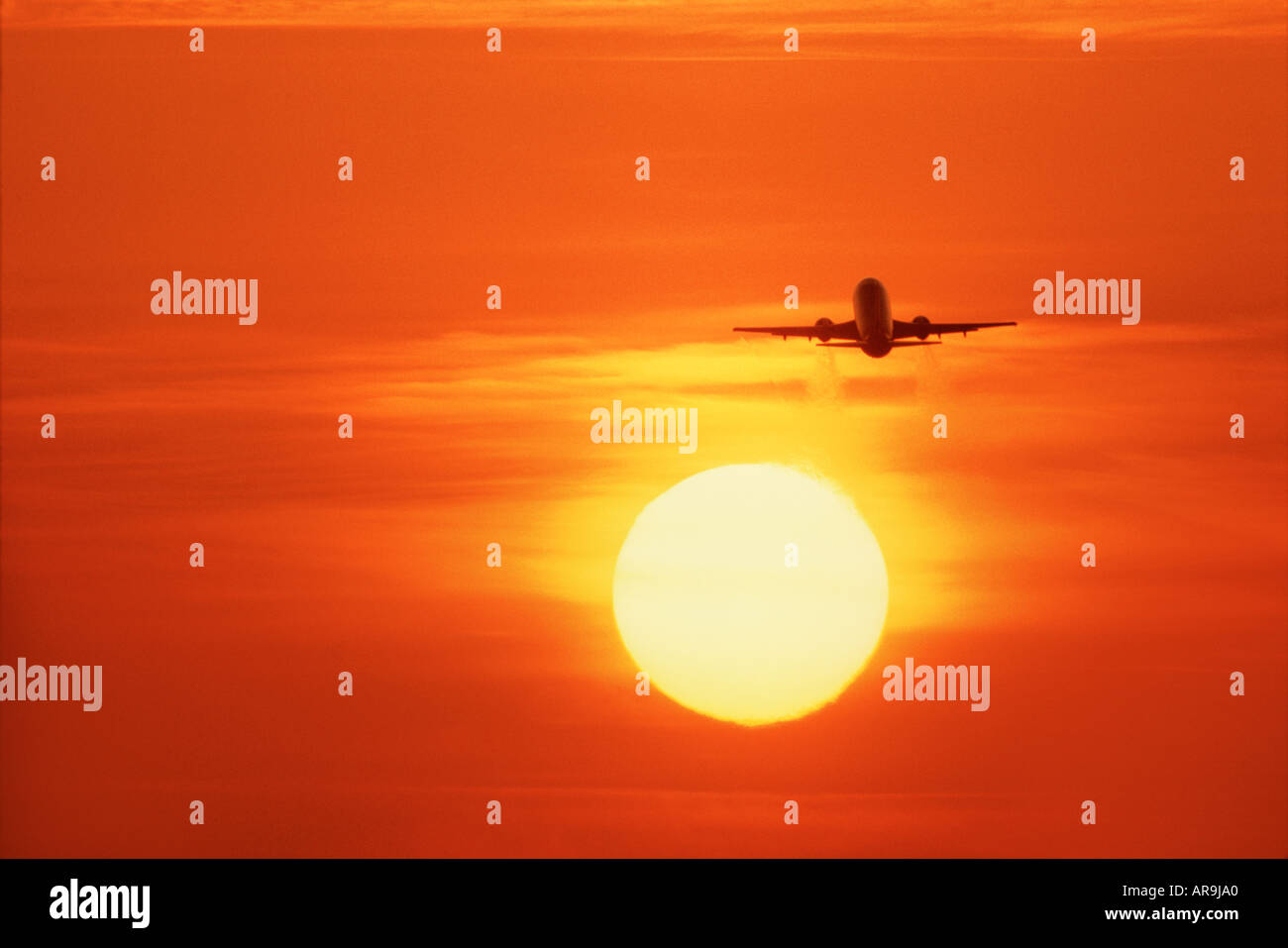 Boeing 737 in the air flying into an golden orange sky at sunset ...