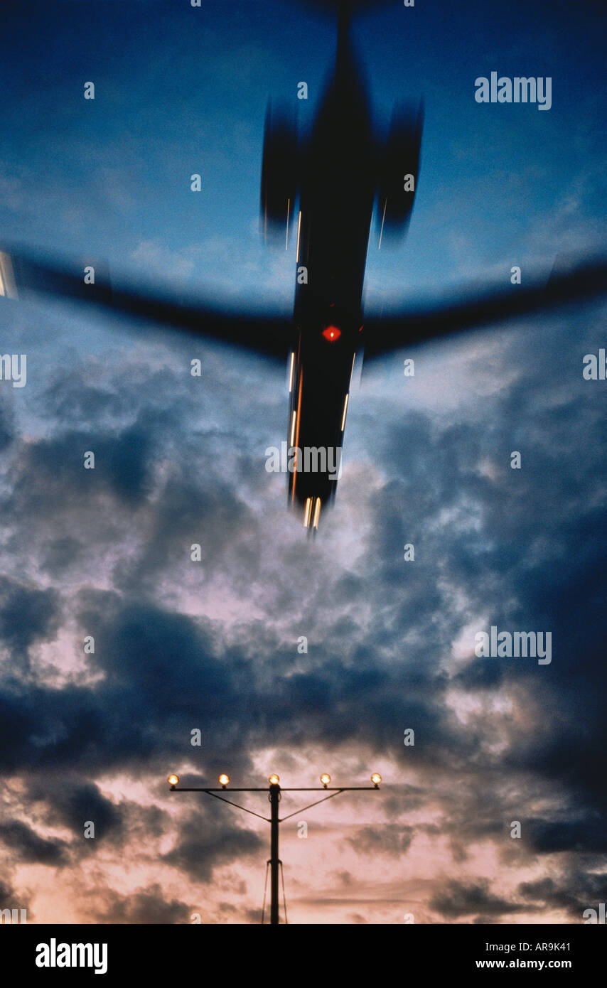 regional jet airliner MD-80 over landing approach runway lights at dusk ...