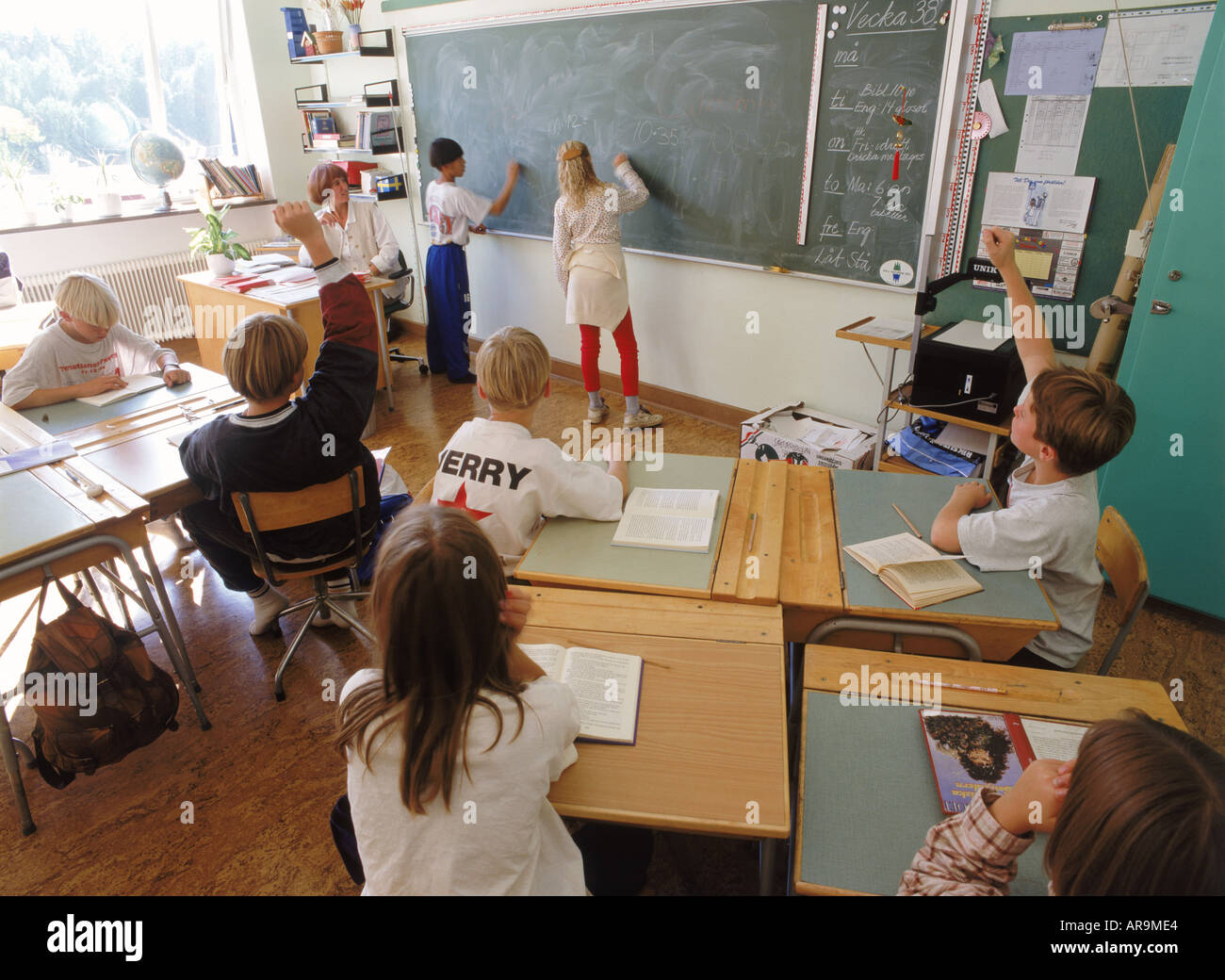 Students in 5th grade Swedish classroom writing on blackboard during ...