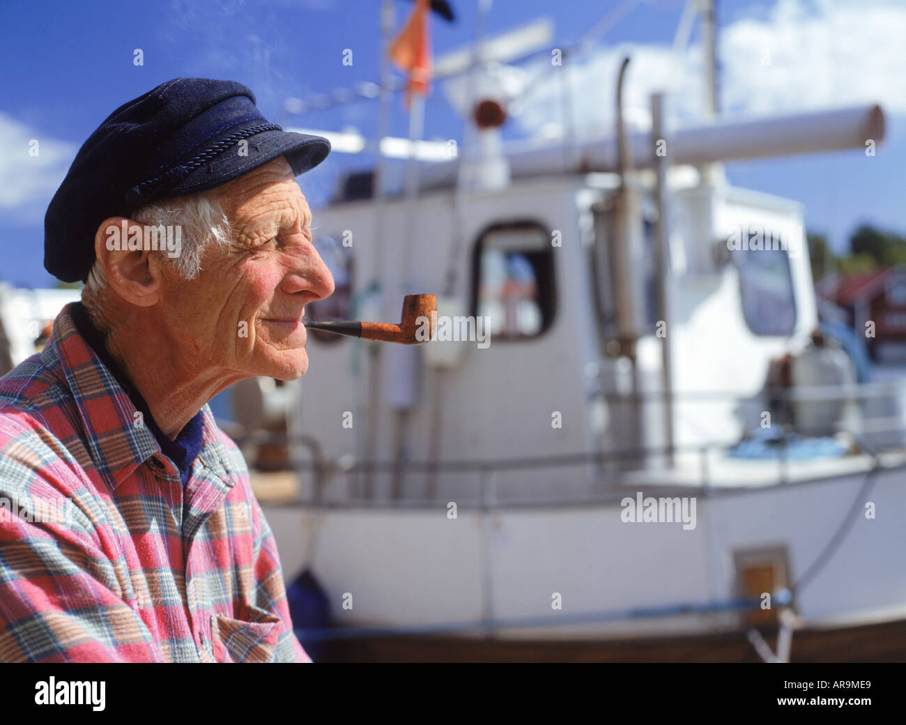 Profile of elderly fisherman with pipe and fishing boat at Kuggoren in ...