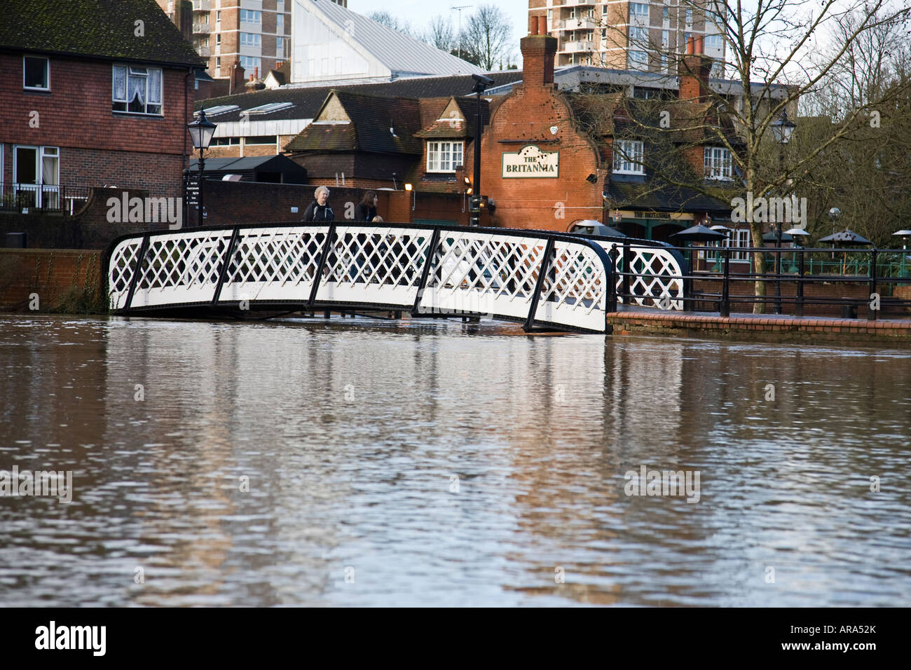 Pedestrians cross a bridge over the flooded River Wey at Guildford ...