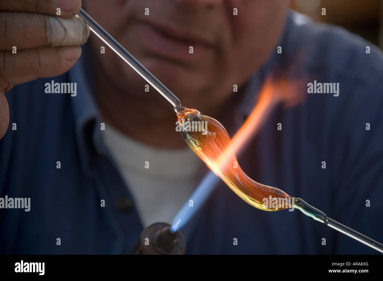 Glass artist melting and re shaping glass with the aid of a Bunsen ...