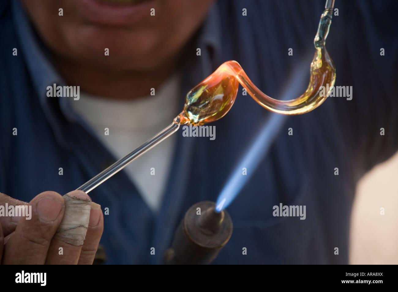 Glass artist melting and re shaping glass with the aid of a Bunsen ...