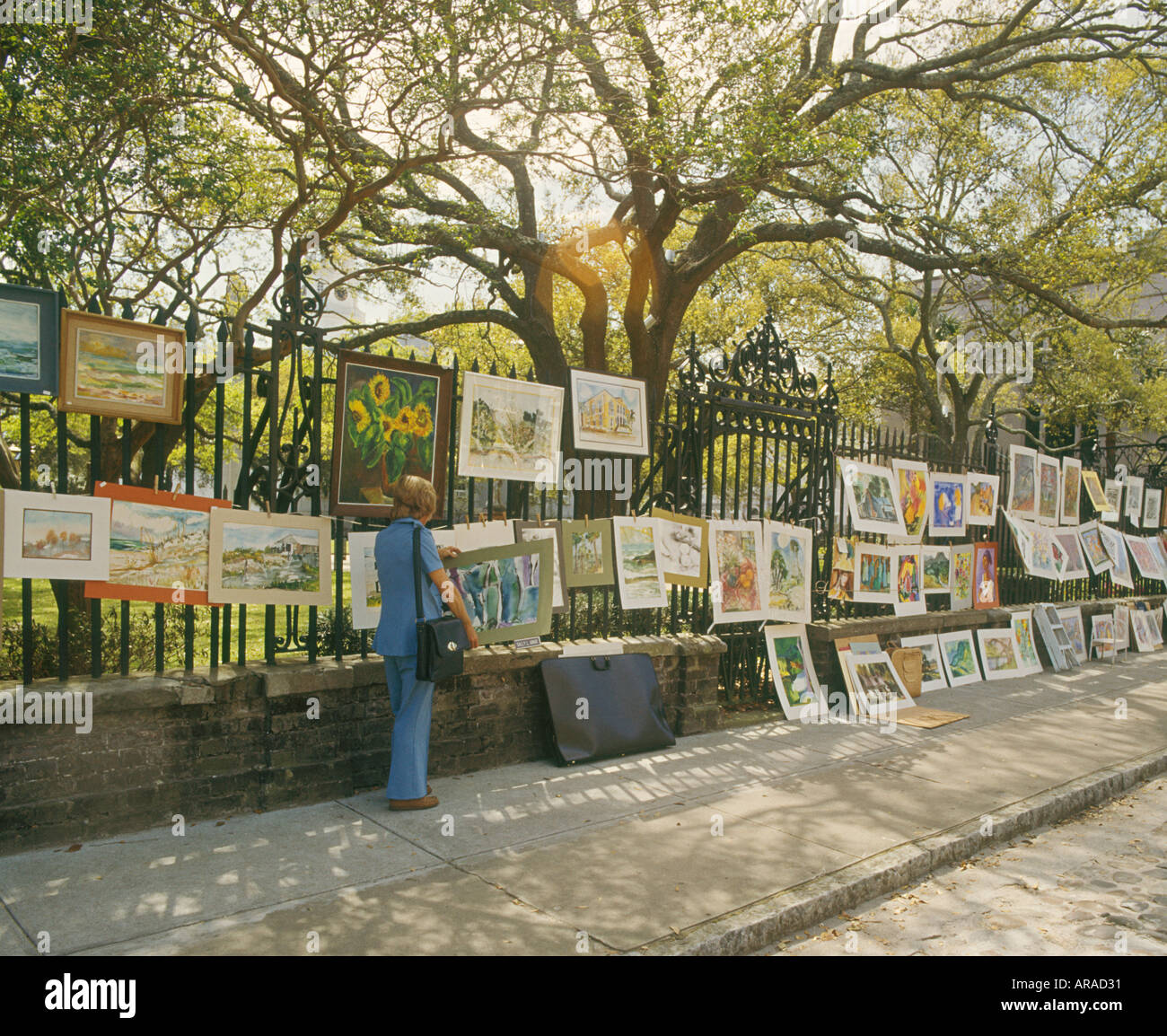woman shopping at an outdoor art display by the Seine River in Paris ...
