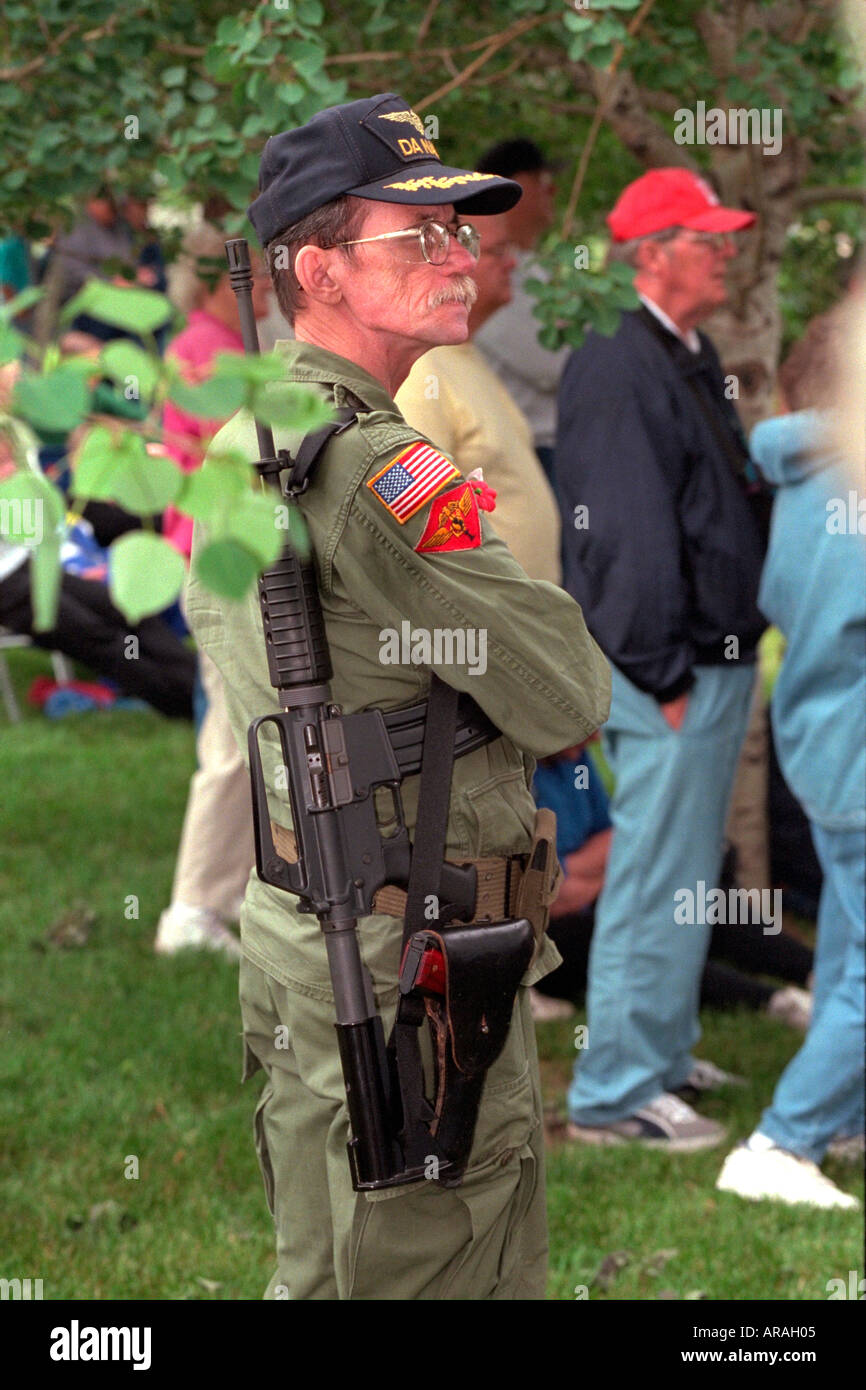 Vigilant veteran age 55 with gun in uniform at Memorial Day service. St ...