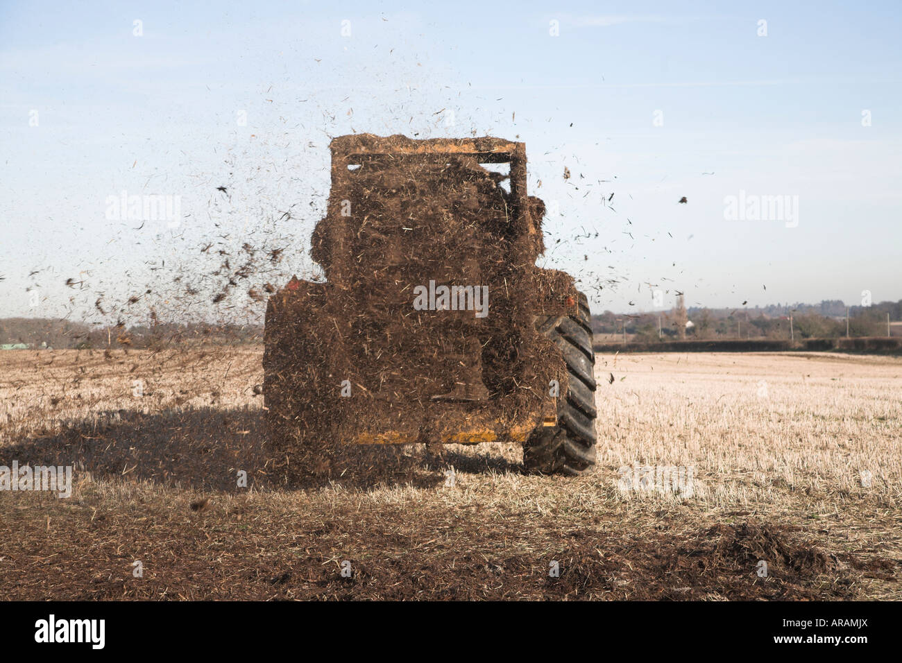 Rear view of tractor muck spreading over field of stubble Stock Photo ...