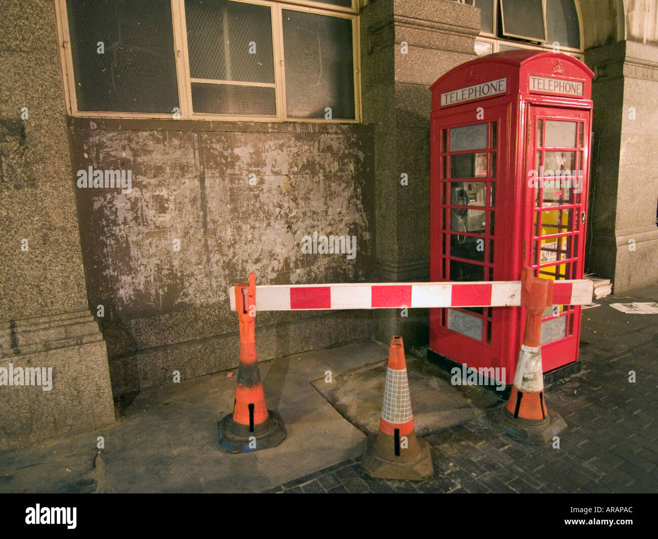 Red telephone box booth at night with empty spot where second one once ...