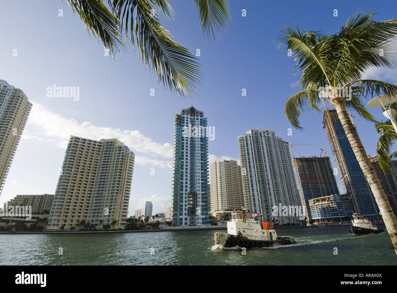 Tug boats navigate high rise building canyon along tropical Miami River ...