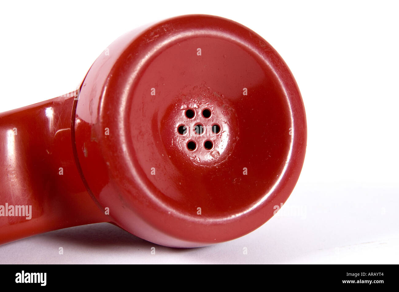 a red dial telephone receiver ear piece end shot from above on white ...