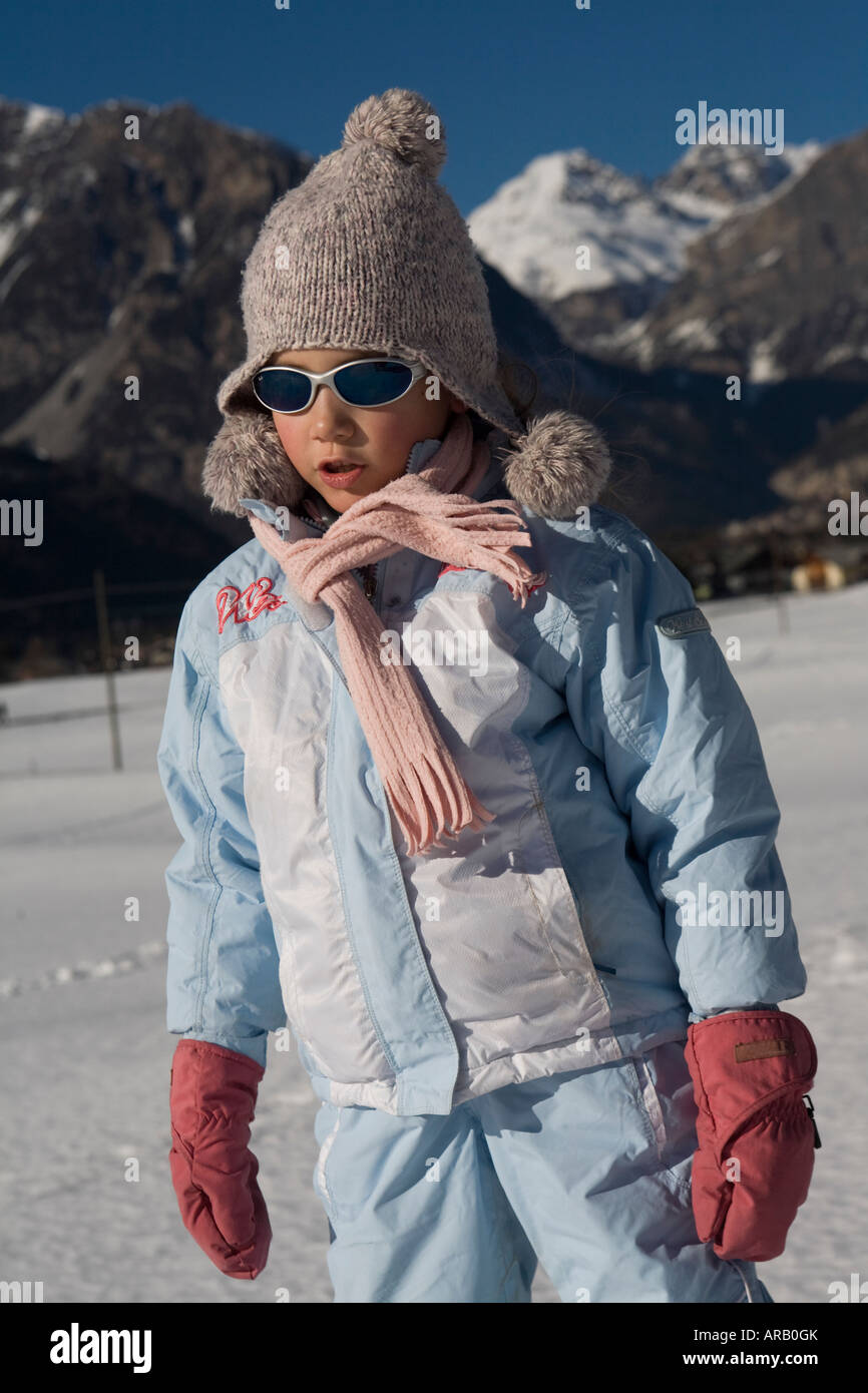 Little girl wearing ski suit in an open field covered with snow in ...