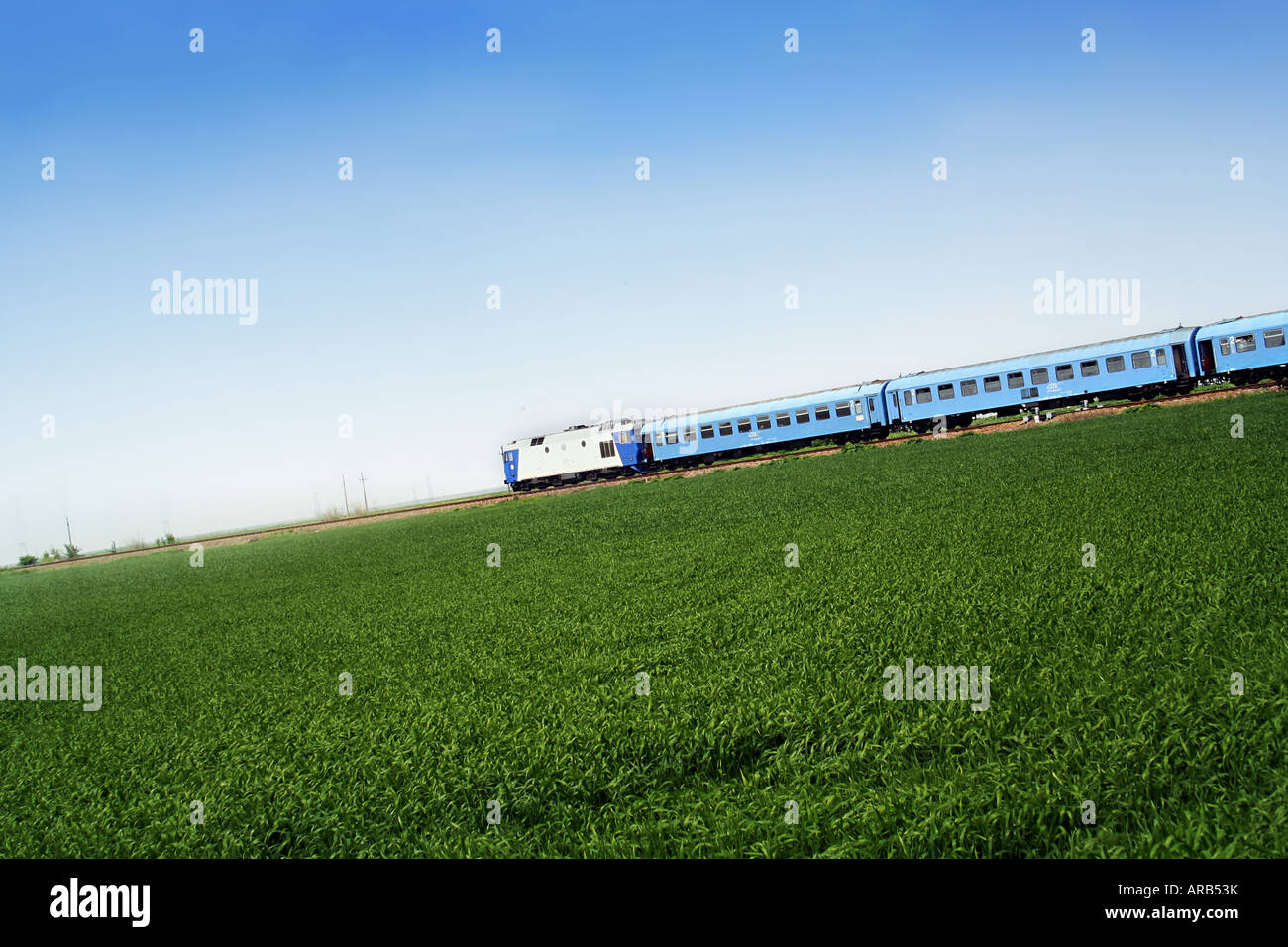 Blue train crossing the field Stock Photo - Alamy
