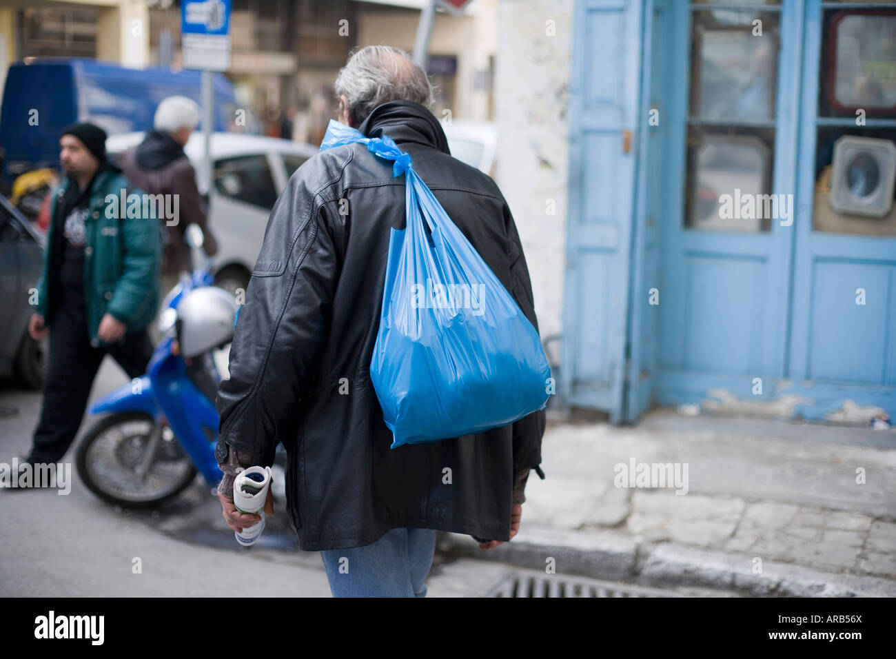 old poor man with a bag on his back walking the street Stock Photo - Alamy