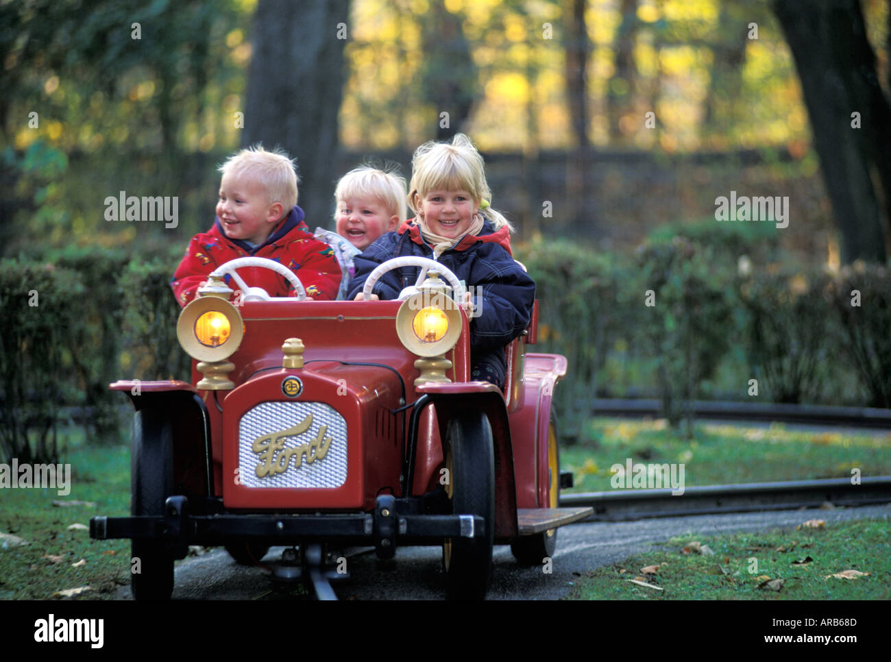 Three children driving in a toy car MR Stock Photo - Alamy
