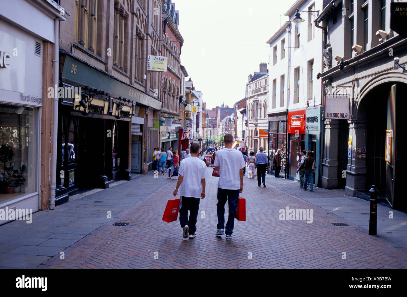 Two males walking down a pedestrian street with matching shirts and ...