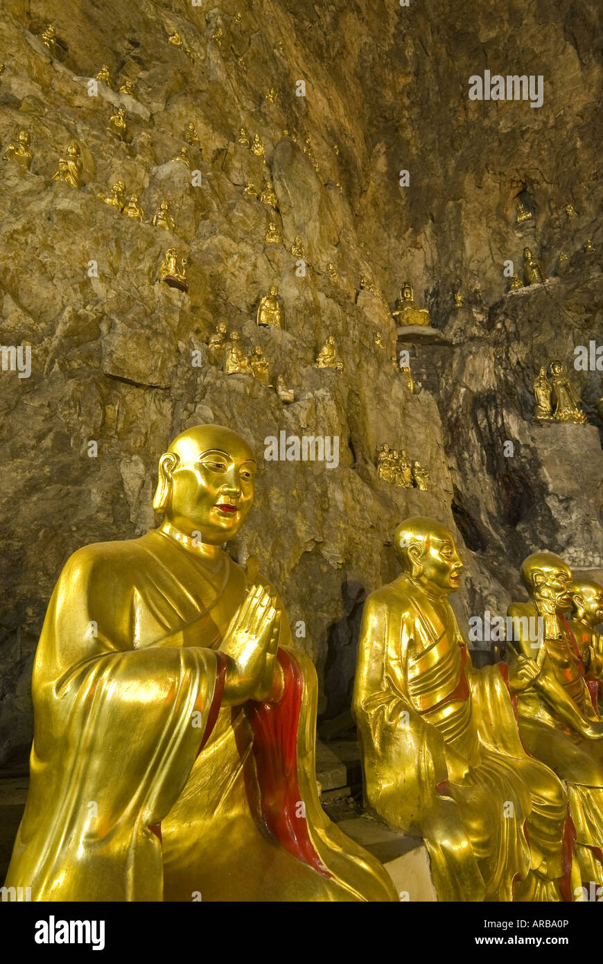 Golden Buddha statues line stone walls of temple cave, Yangdang ...