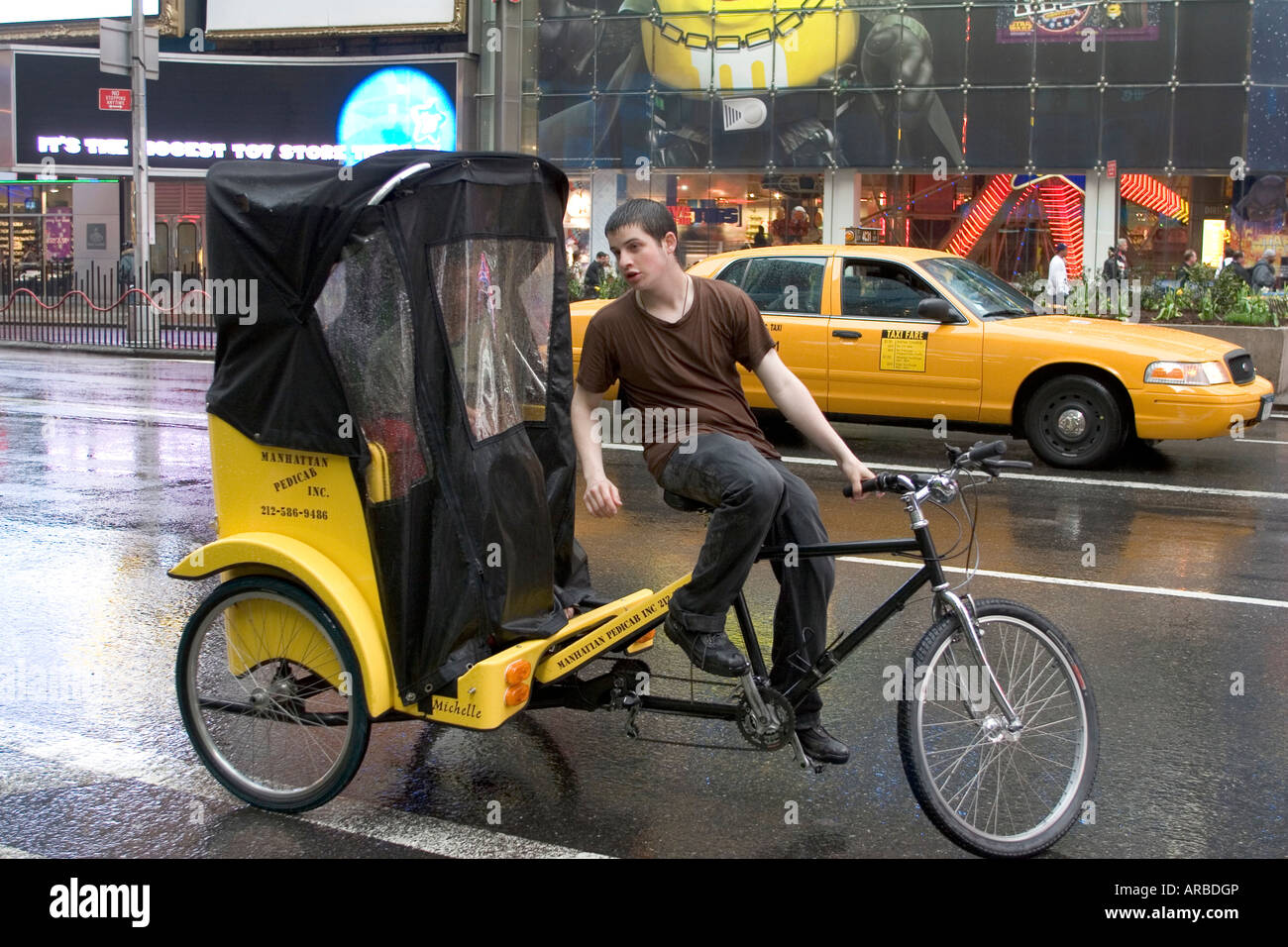 New York City pedicab driver talks with a passenger in the rain while ...