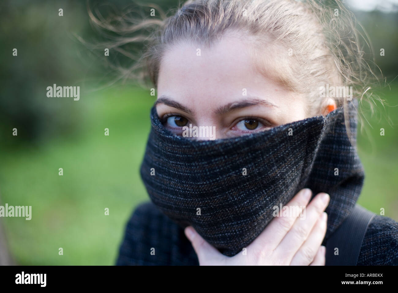 portrait of a young woman covering half of her face suggesting that she ...