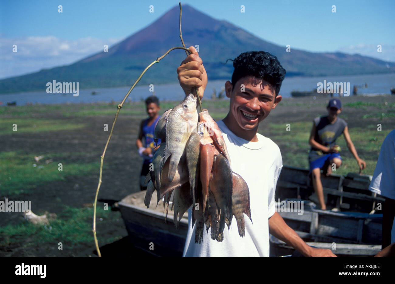 Young man showing fish caught in Lake Managua in the back Momotombo ...