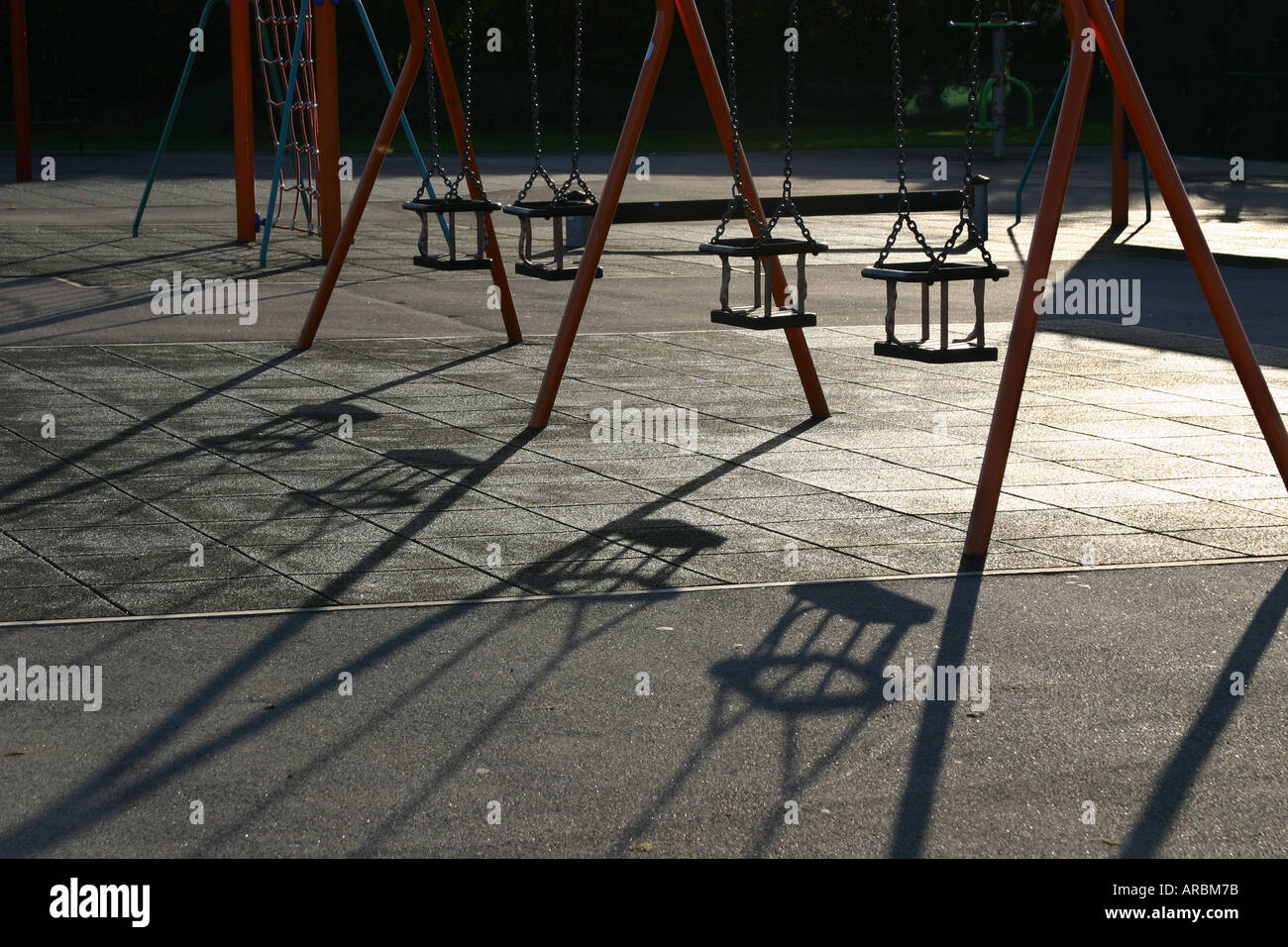 Strong shadows of swings in childrens playground in morning sun Stock ...