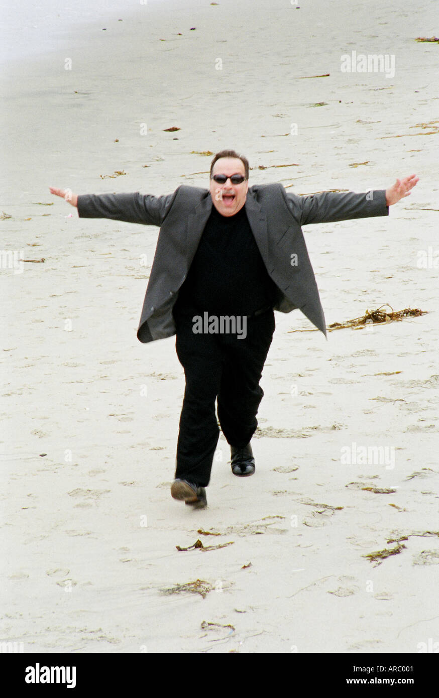 Man in suit running with arms out like an airplane on the beach Stock ...