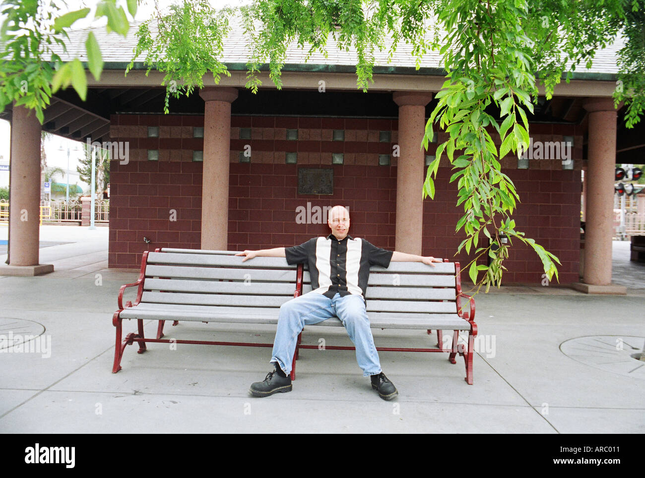 Man sitting on bench looking bored Stock Photo - Alamy