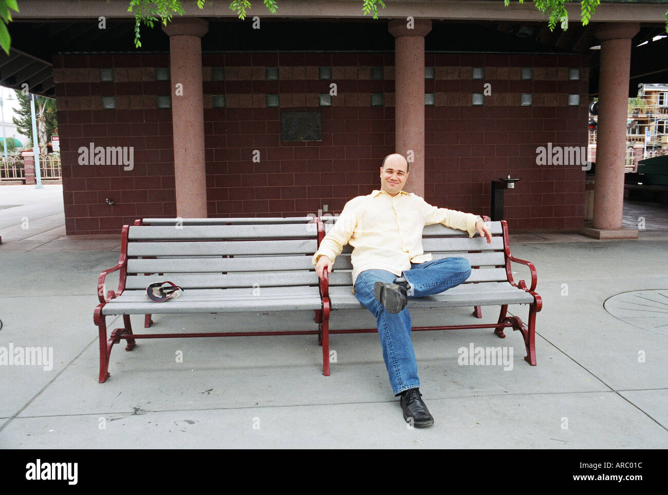 Man in jeans sitting on a bench Stock Photo - Alamy
