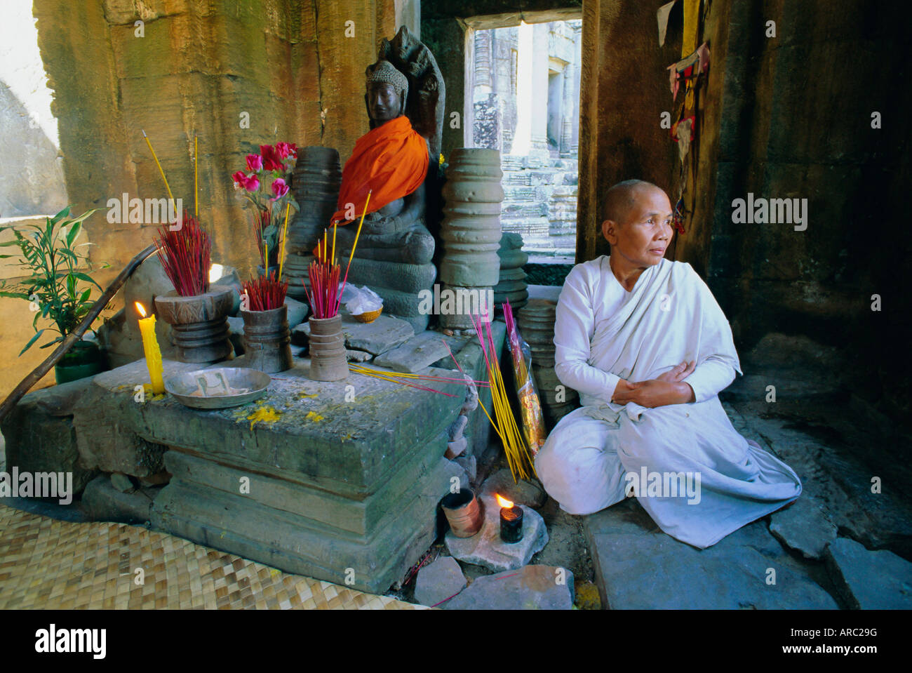 Buddhist nun meditating in the Bayon Temple, at Angkor, Siem Reap ...