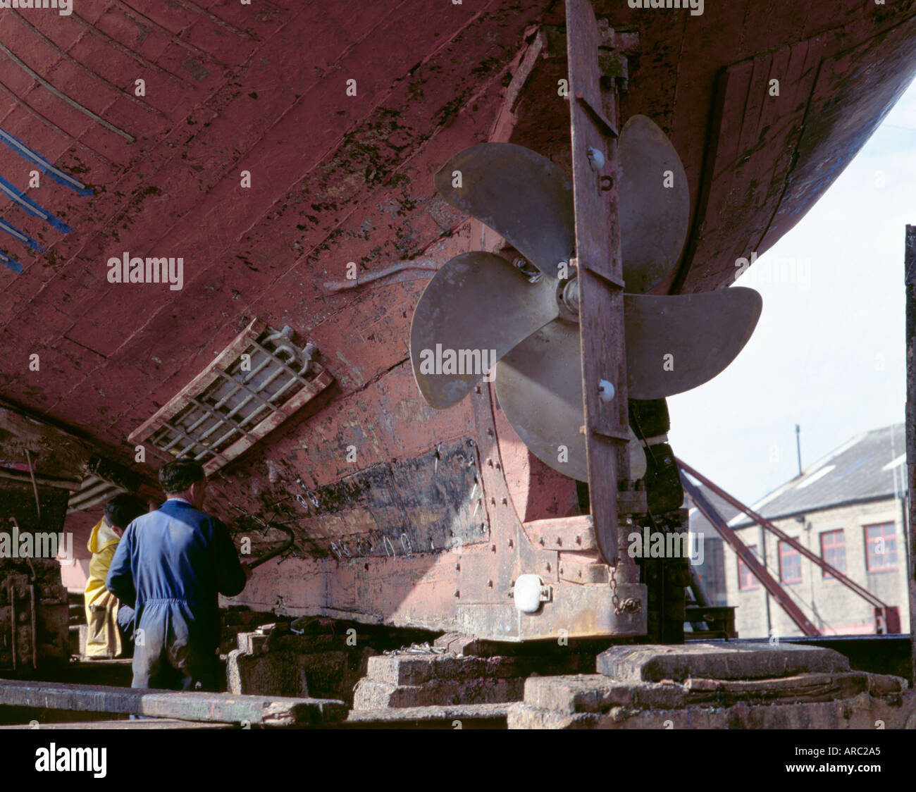 Shipwrights inspecting the hull of a boat in a ship repair yard ...