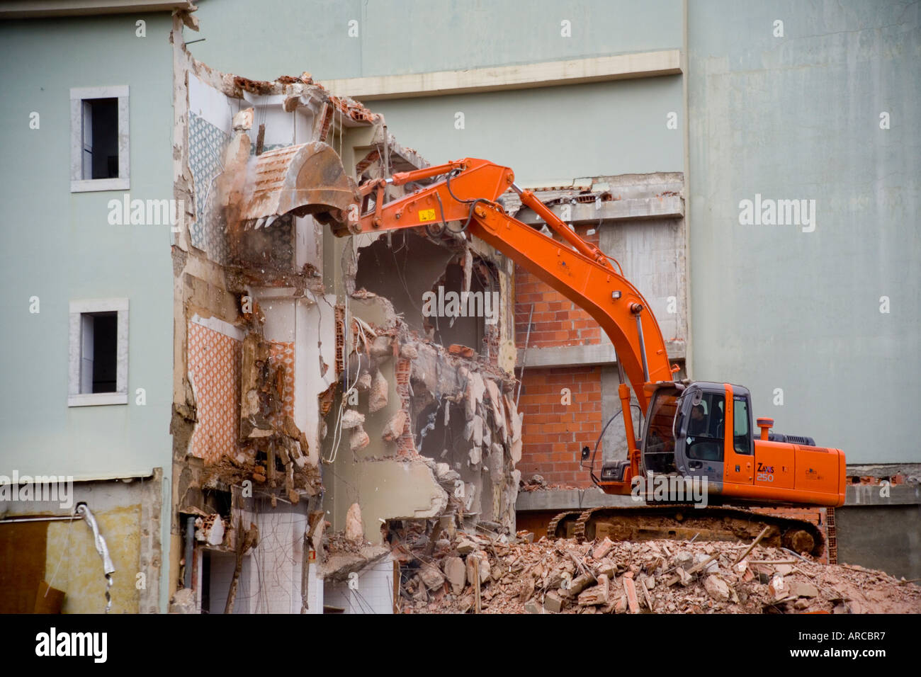 A backhoe is used to demolish a reinforced concrete building in Fatima ...