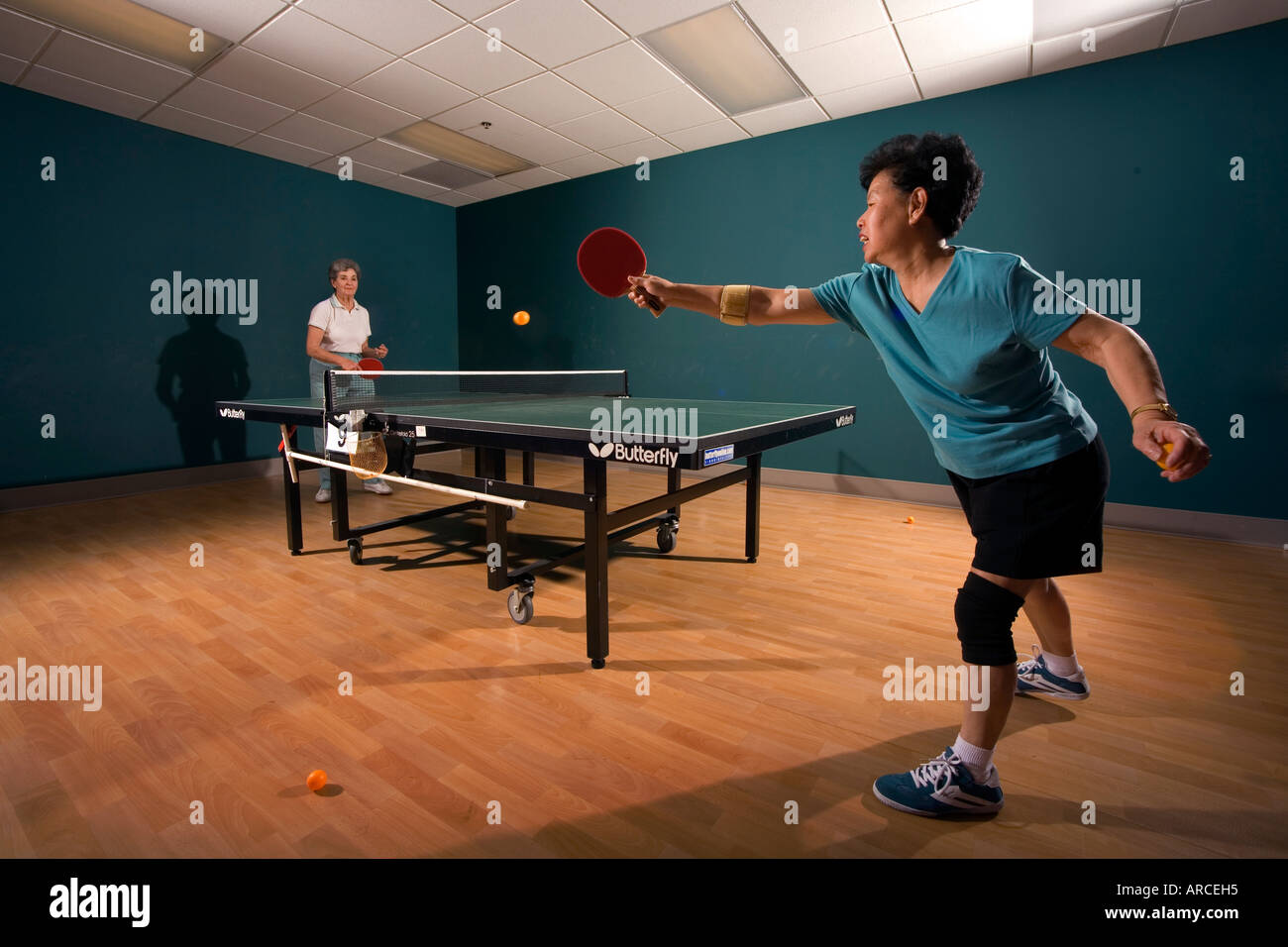 Two women over age 70 play ping pong at a seniors athletic facility ...