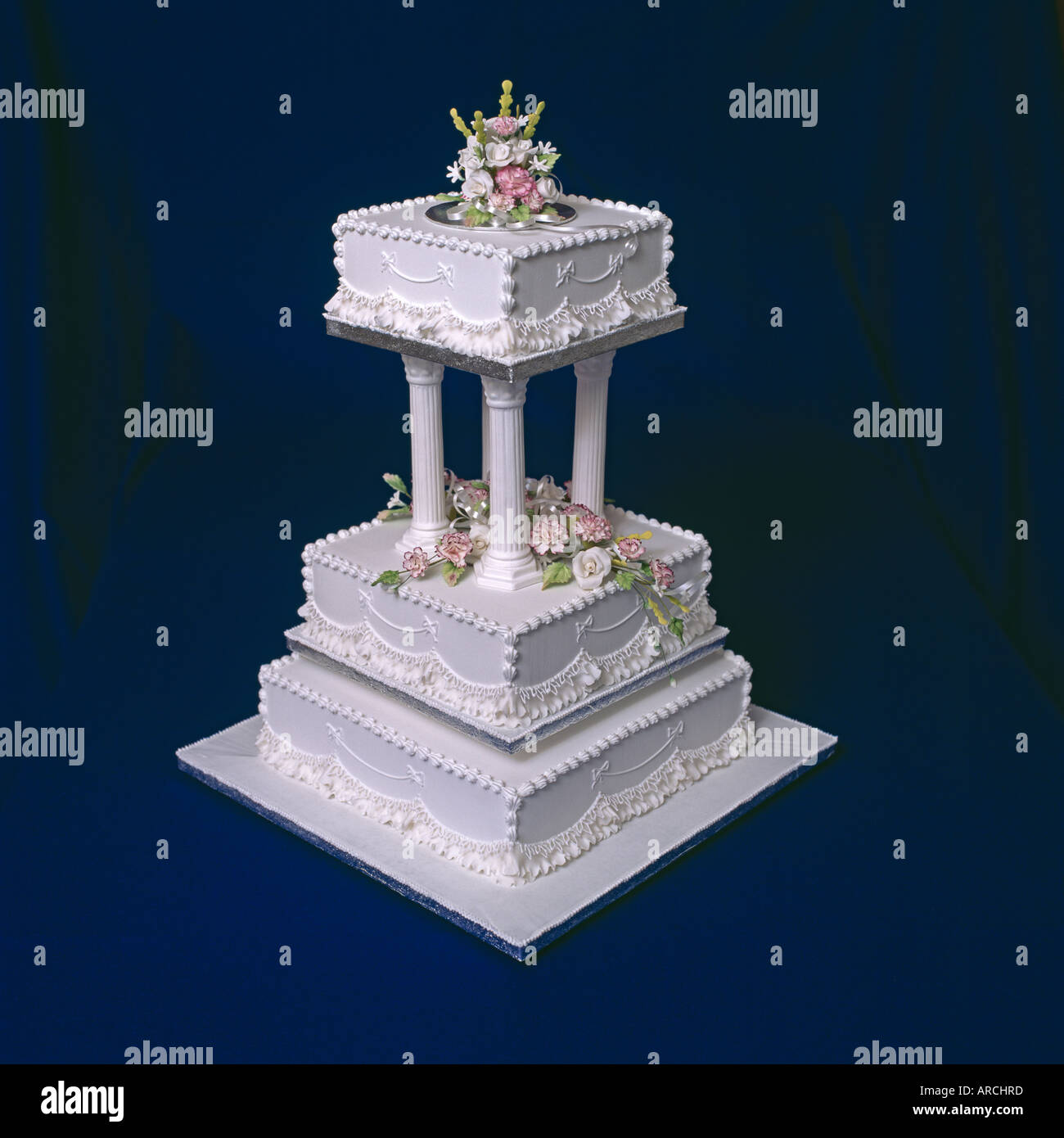 Tree-tier wedding cake, royal iced, with long columns supporting top ...